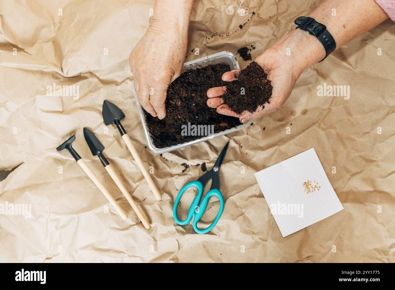 Kraft paper background, fertile soil and garden tools, top view. Hands ...