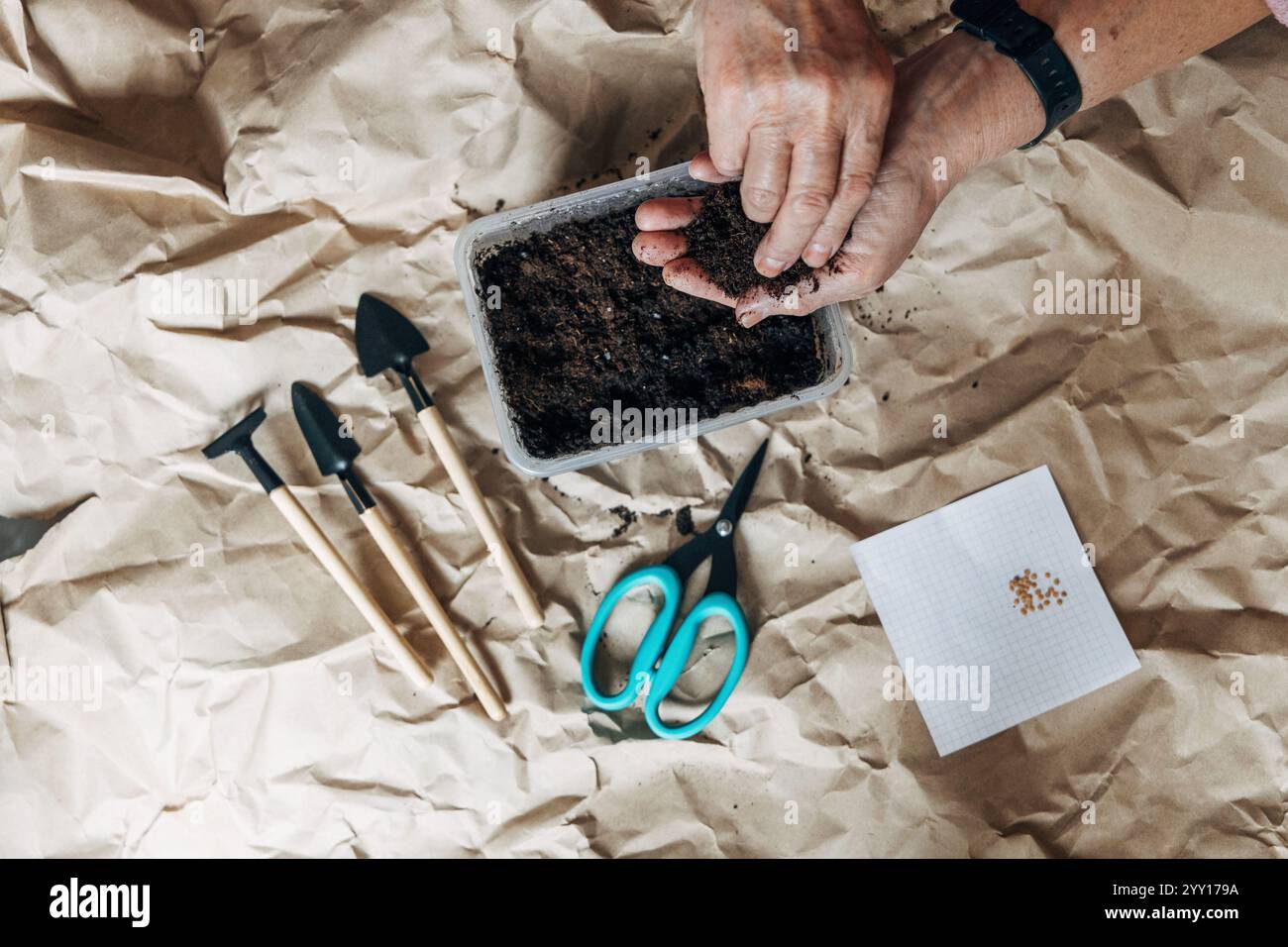 Kraft paper background, fertile soil and garden tools, top view. Hands ...