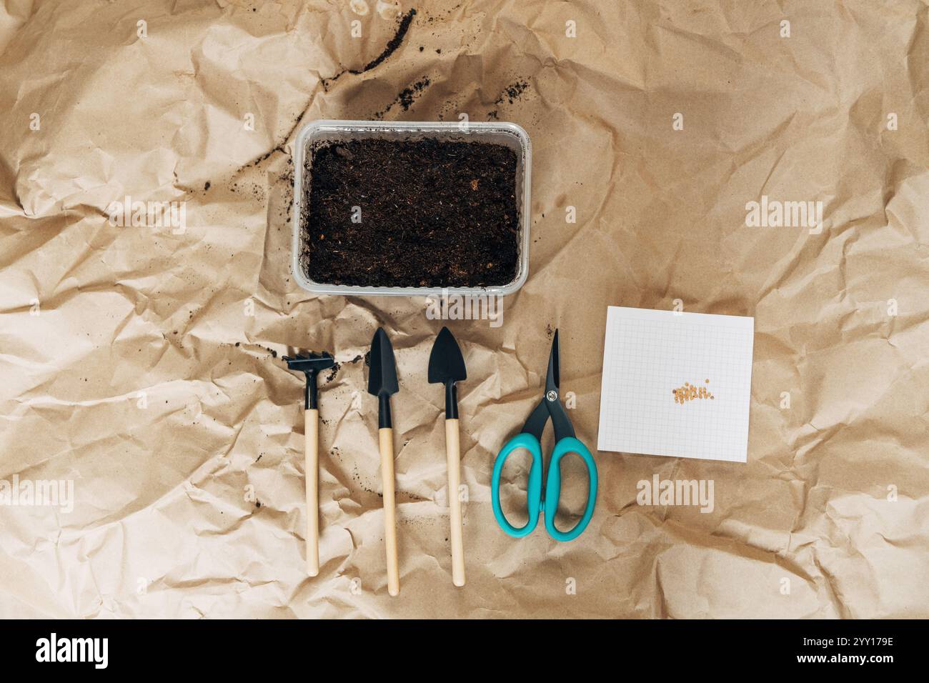 Kraft paper background, fertile soil and garden tools on top, top view ...