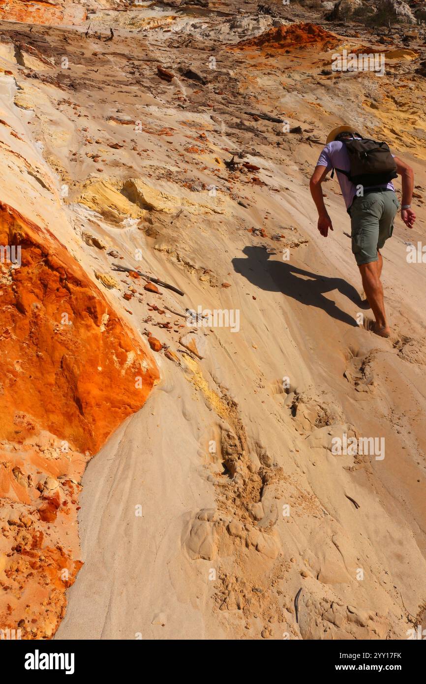 Tourist climbing the colored sand cliffs in Rainbow Beach, Queensland ...