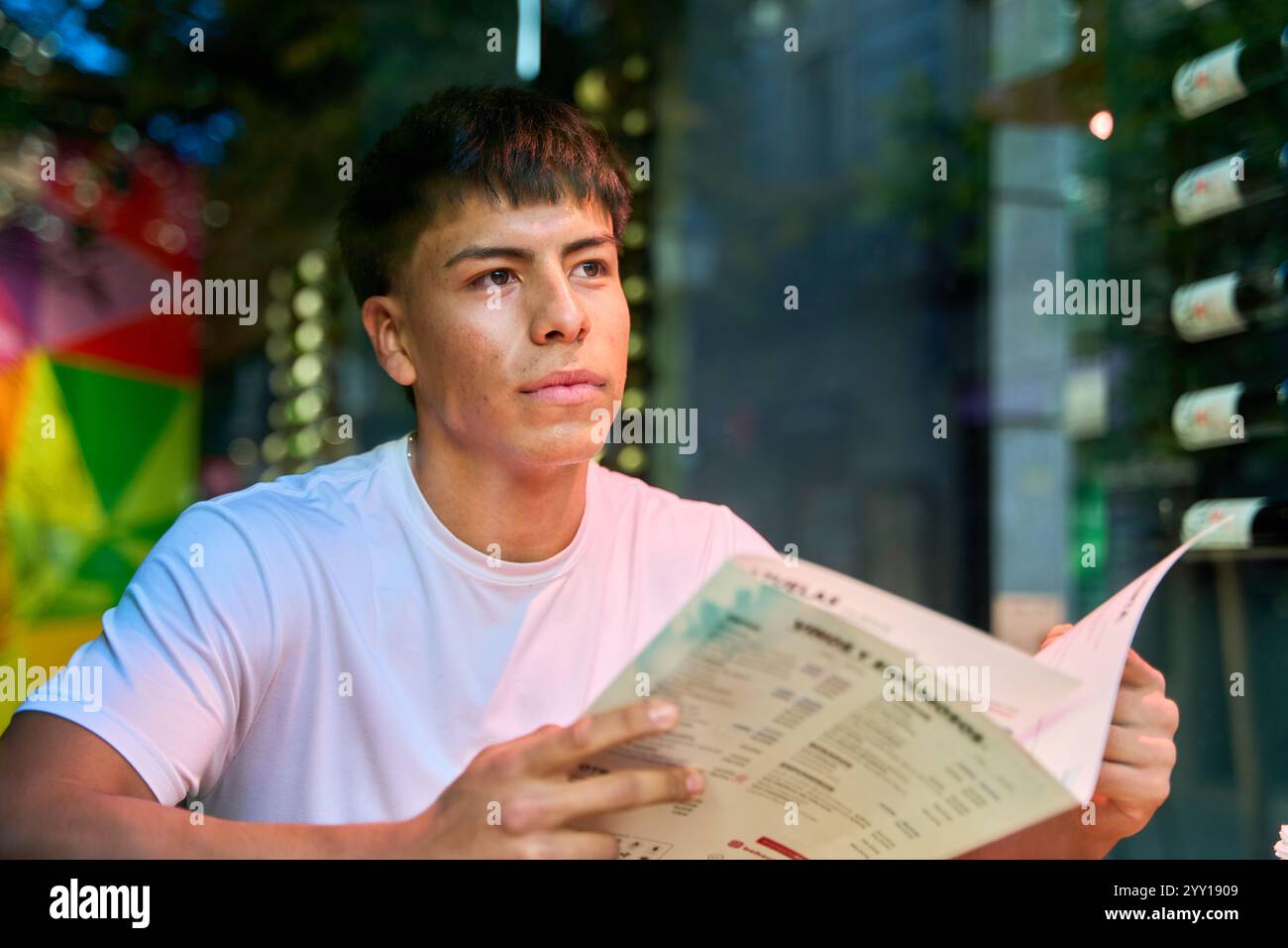 Young Latino man reading menu at cafe with thoughtful expression Stock ...
