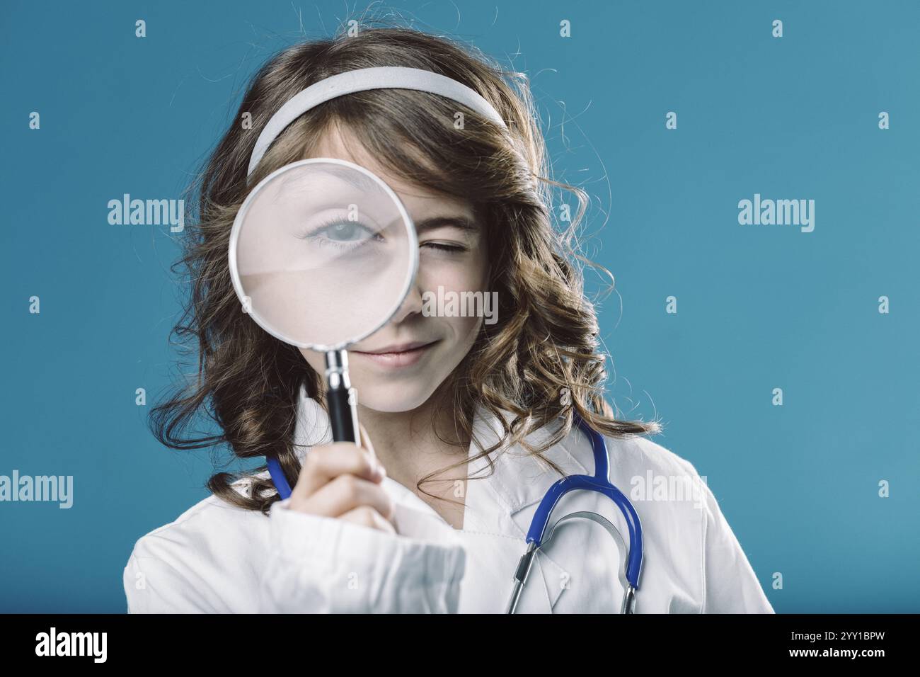 Curious young aspiring doctor winking while looking through a ...