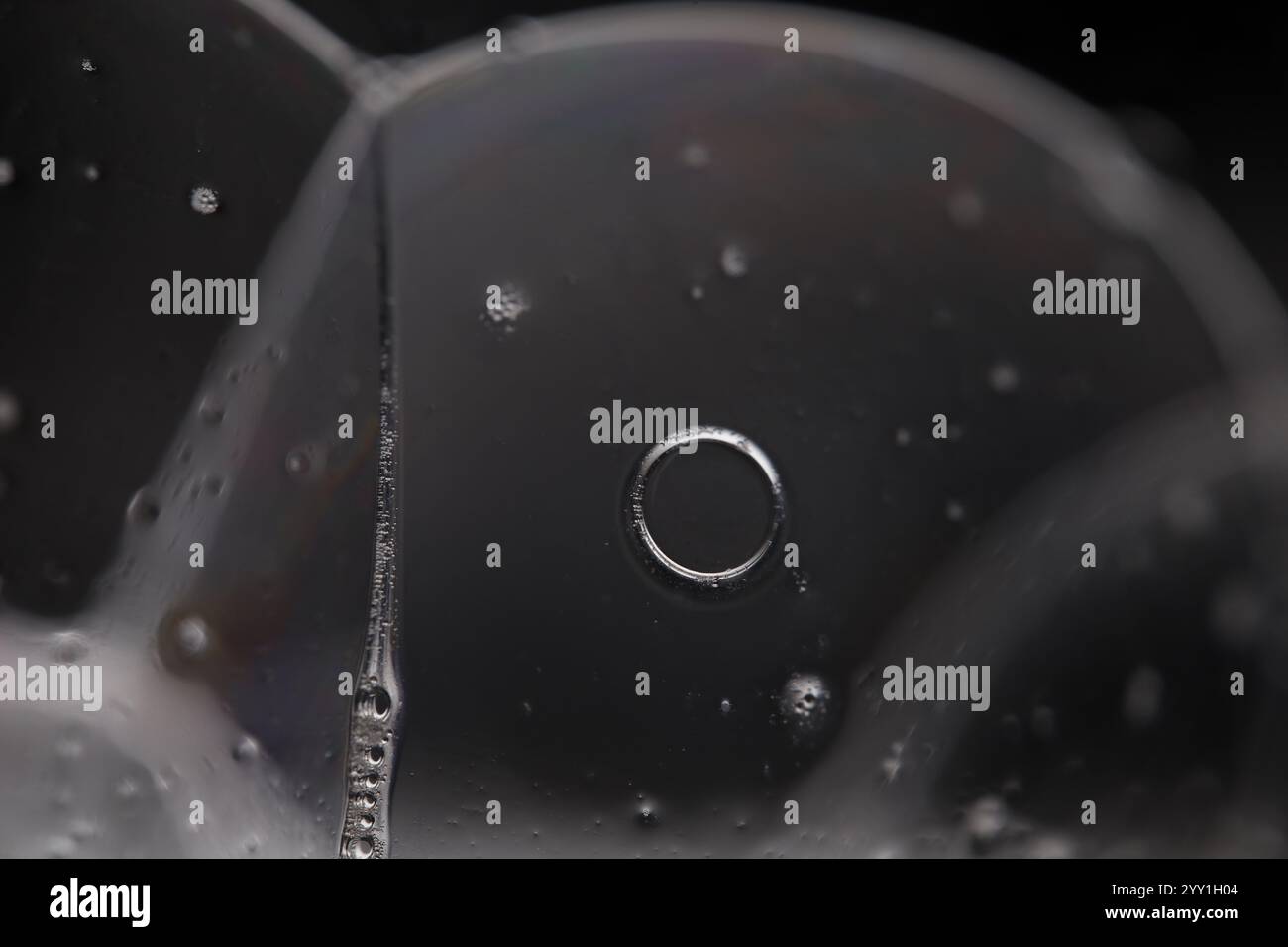 Transparent liquid, bubbles of thick liquid, silver reflection on dark ...