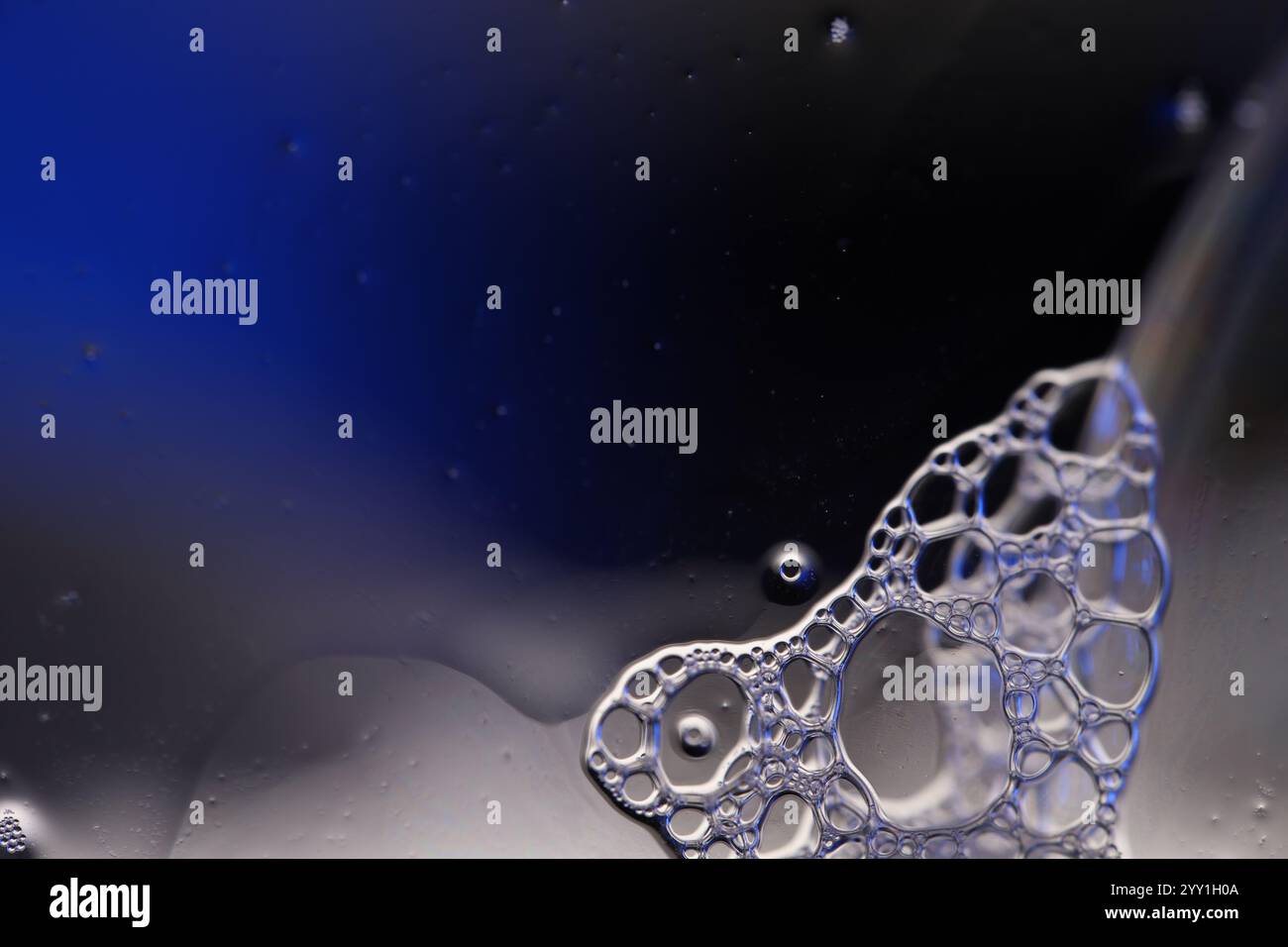 Transparent liquid, bubbles of thick liquid, silver reflection on dark ...