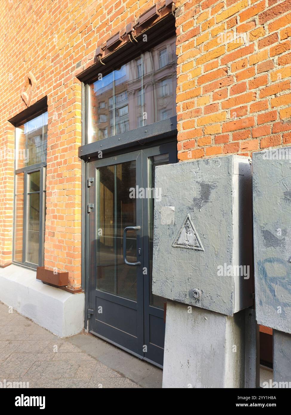 A red brick building with large modern windows and a worn-out ...