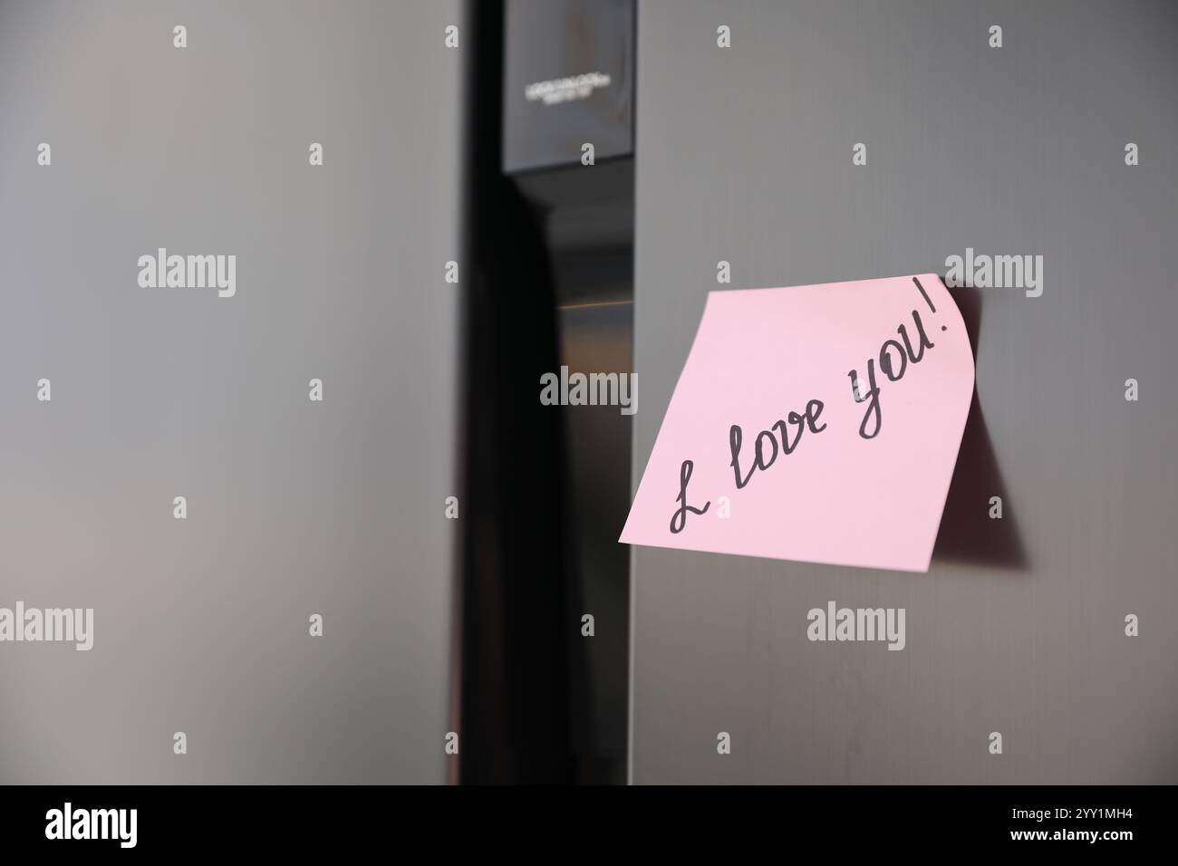 Sticky note with handwritten text I Love You attached to fridge door ...