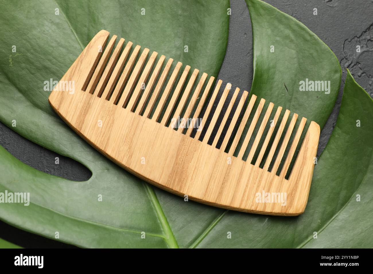 Wooden comb and monstera leaf on dark textured table, top view Stock ...