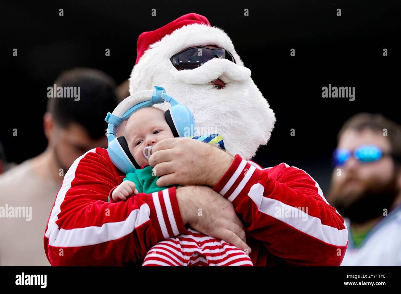 FILE - A fan wearing a Santa Claus beard holds a child during the ...