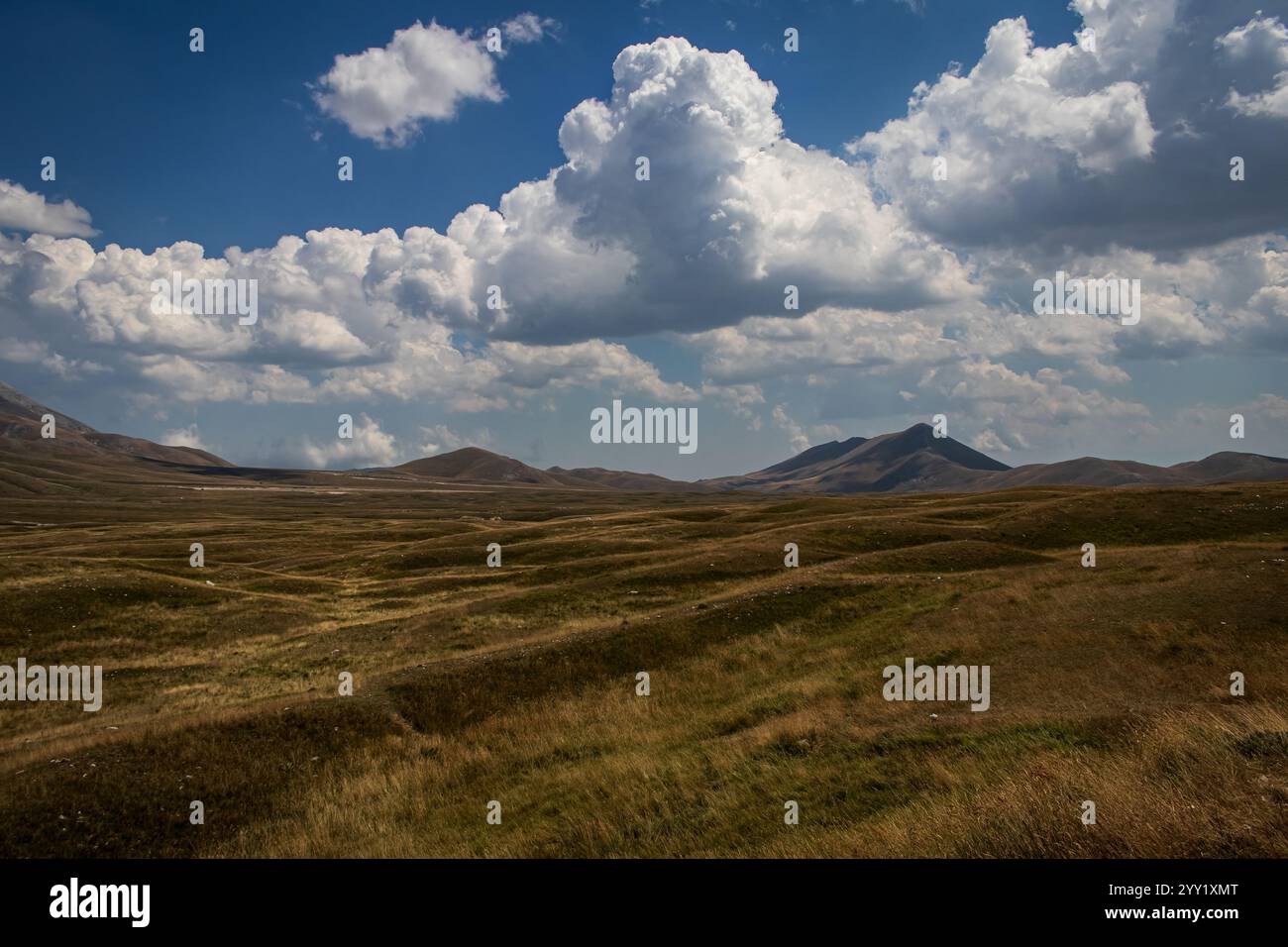 Expansive mountain valley with a dramatic rocky peak under a bright ...