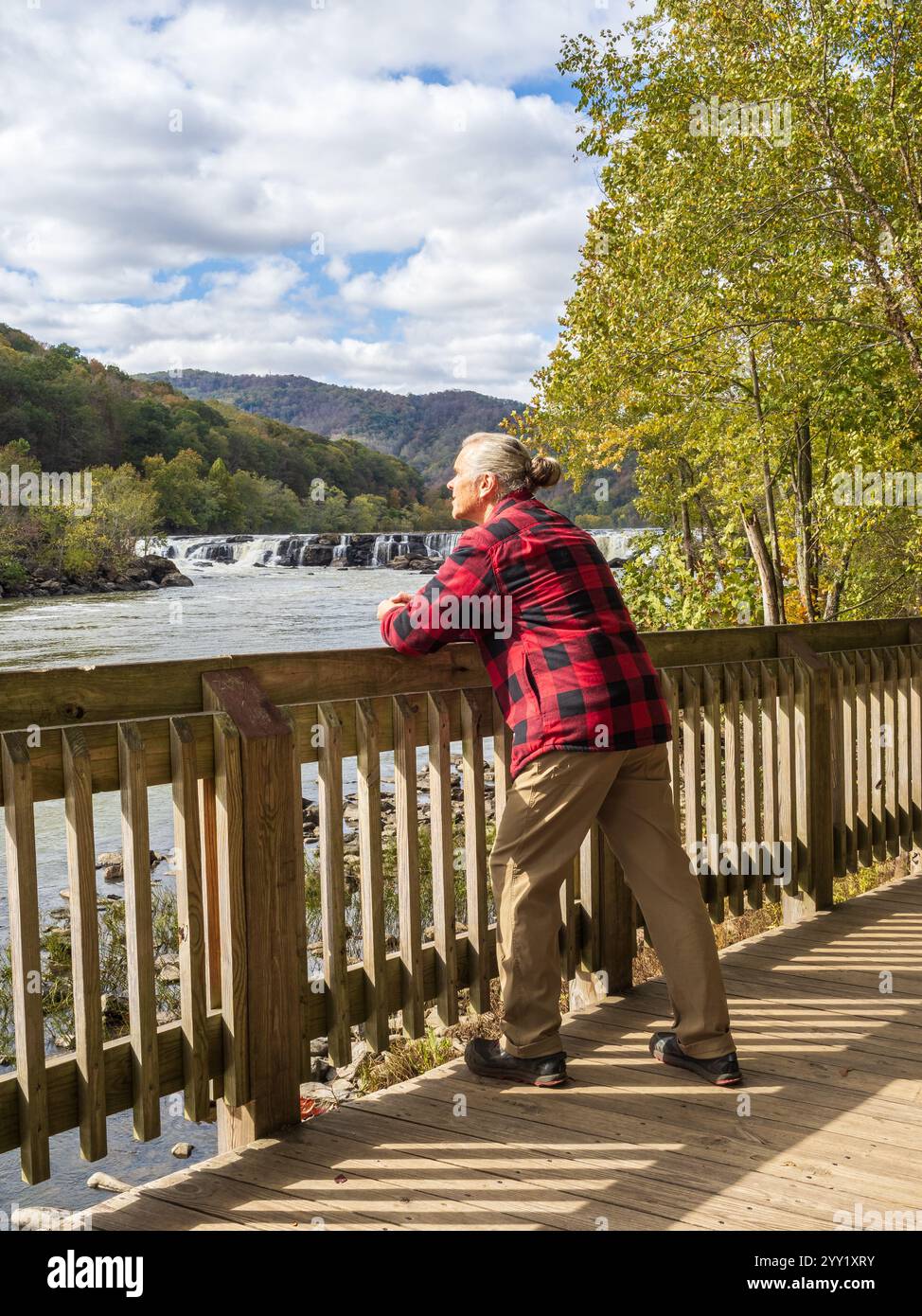 A man in a red lumberjack jacket and hair bun stands in awe of ...
