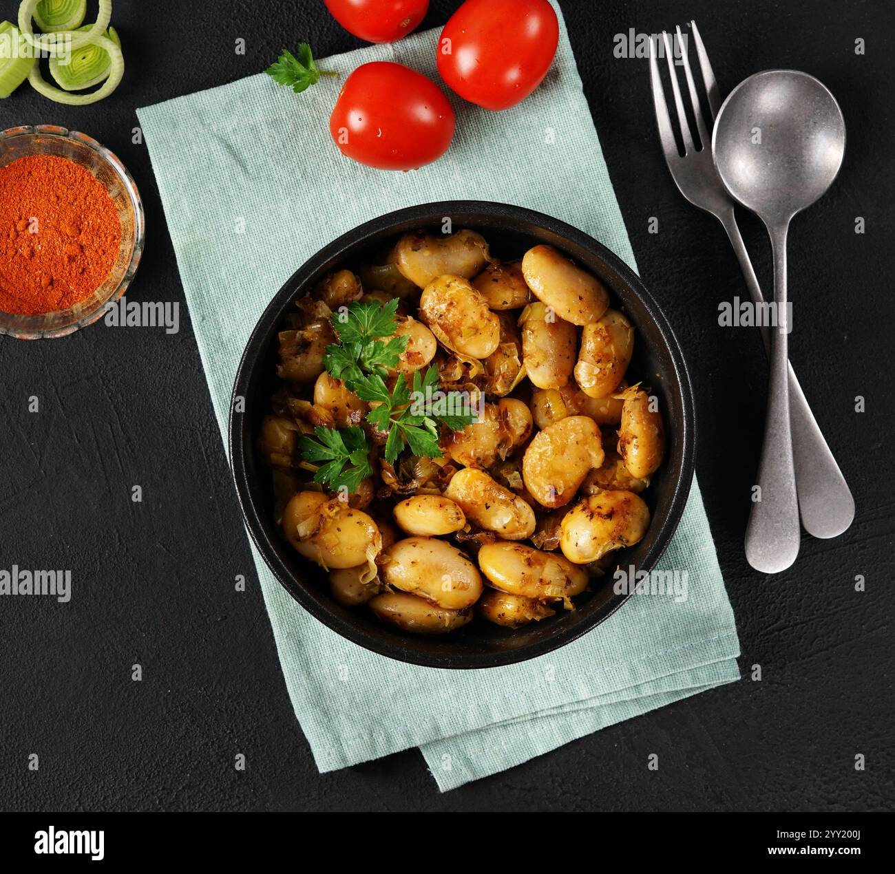 Fried beans with leeks and spices in a black bowl. Rustic style. Top ...