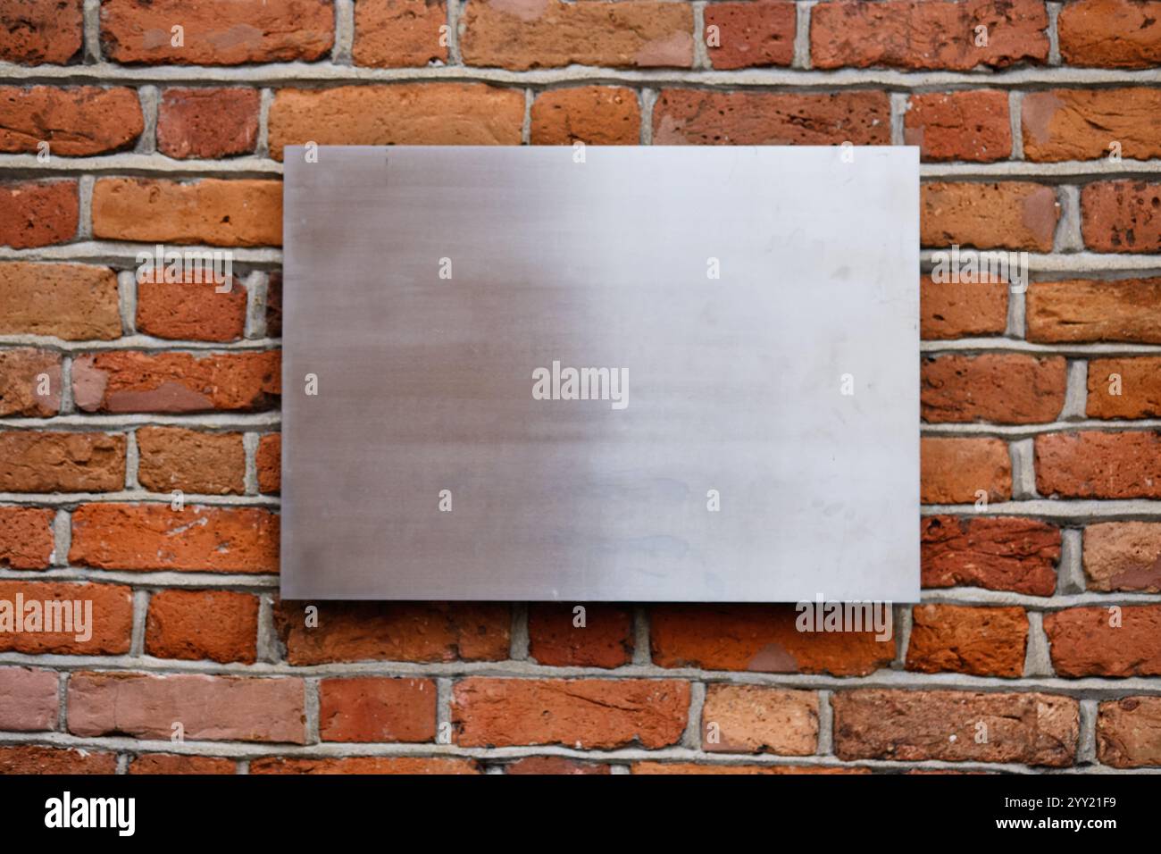 A smooth metal panel is affixed to an old brick wall, showcasing the ...