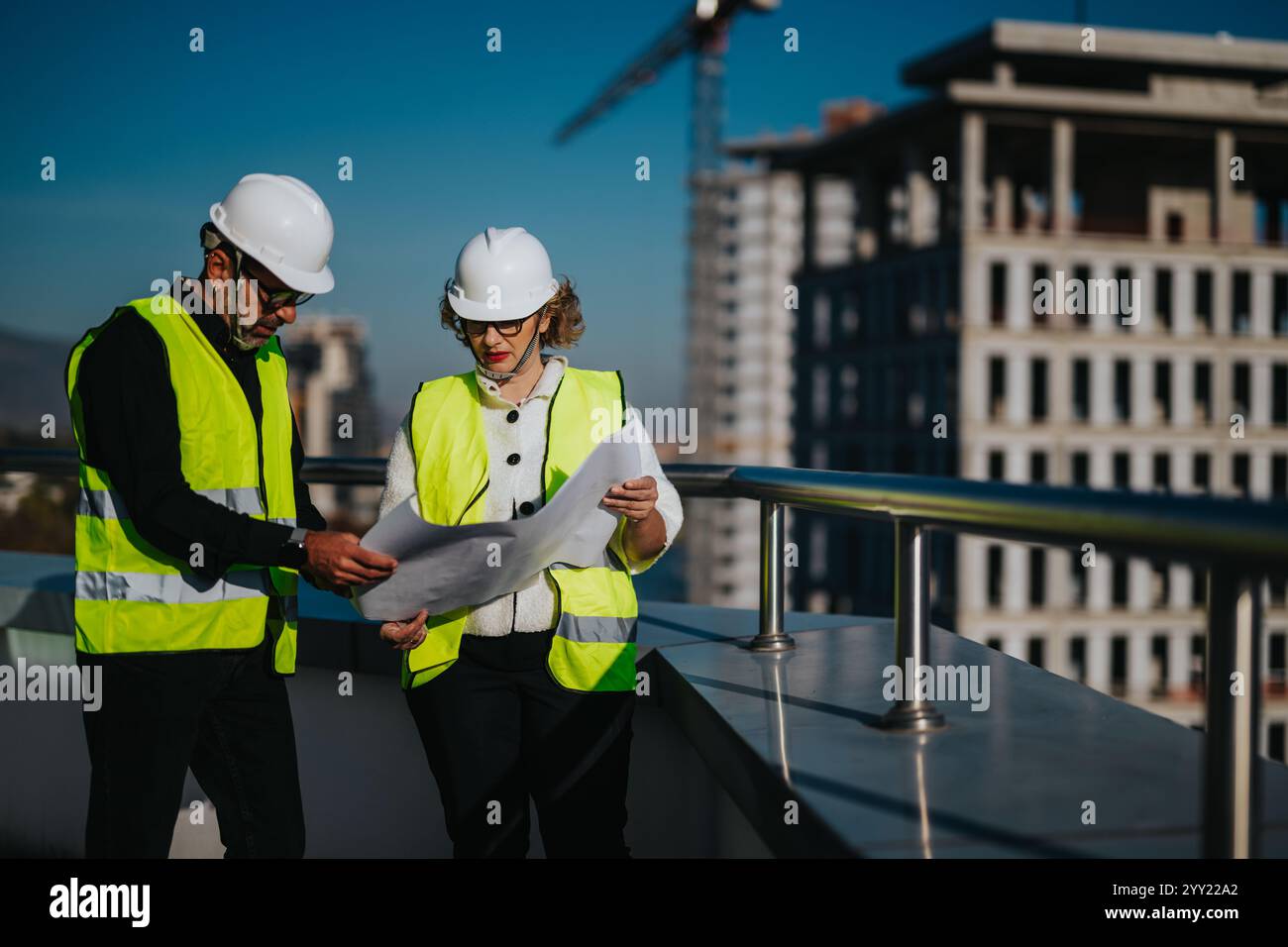 Architects reviewing blueprints on construction site rooftop Stock ...