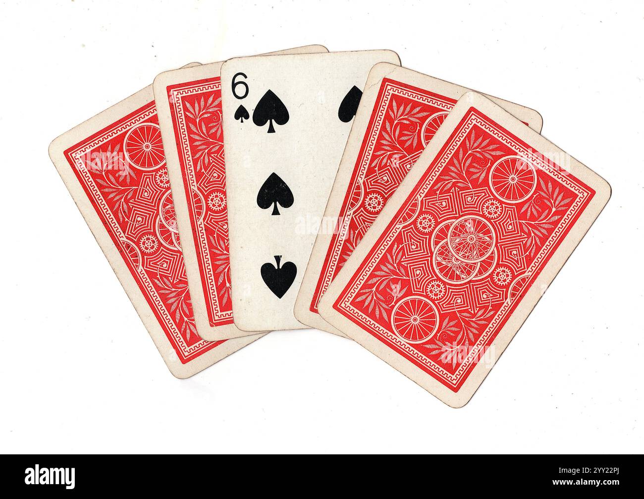 A hand of vintage playing card backs with the six of spades revealed on ...