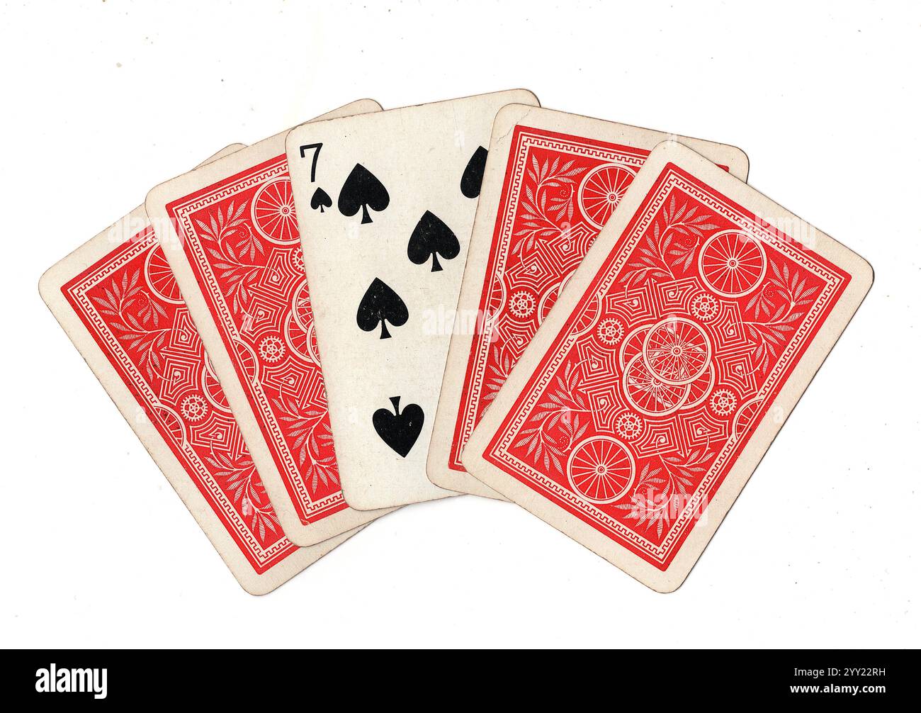 A hand of vintage playing card backs with the seven of spades revealed ...