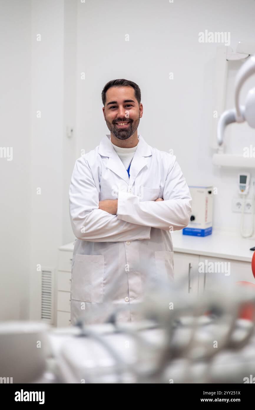 vertical Smiling dentist with arms crossed stands confidently in a ...