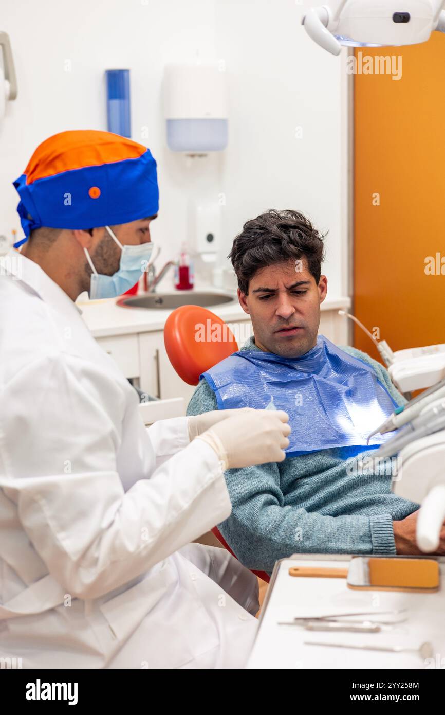 Dentist wearing surgical mask and gloves is preparing a syringe with ...