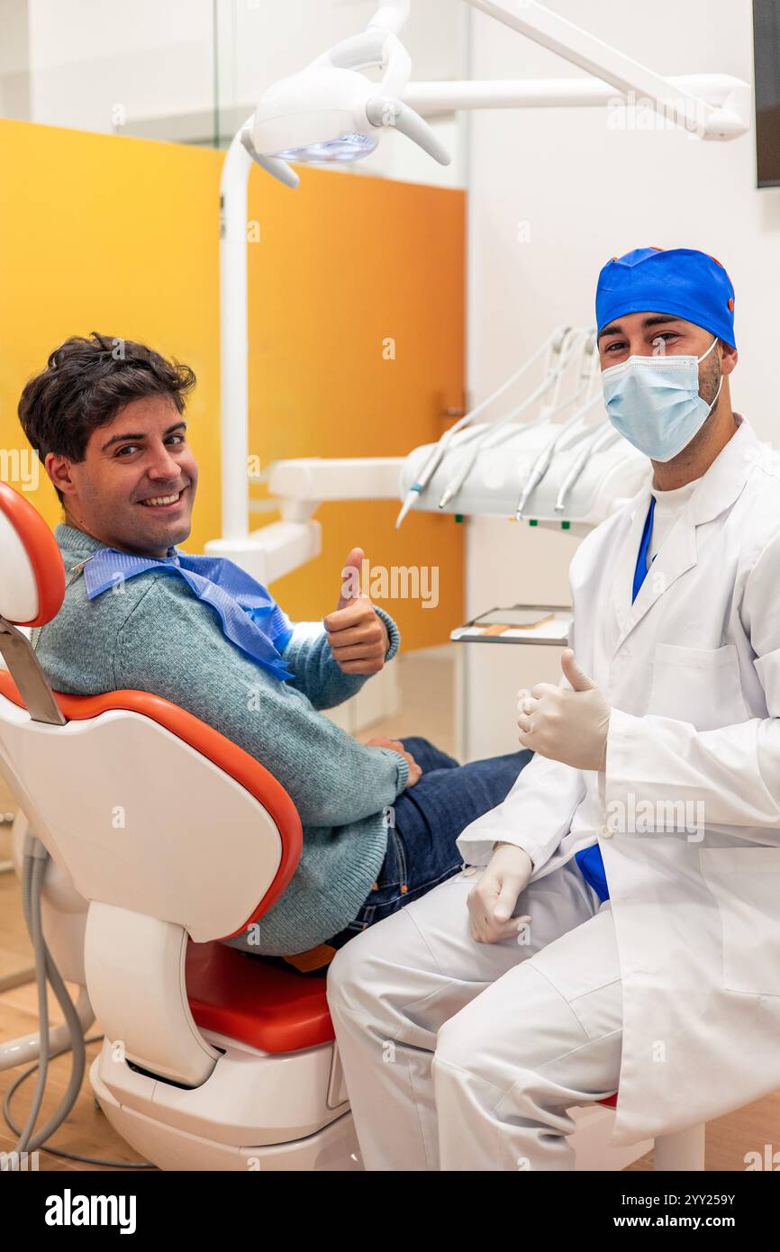 Happy dentist and patient gesturing thumbs up after a successful dental ...