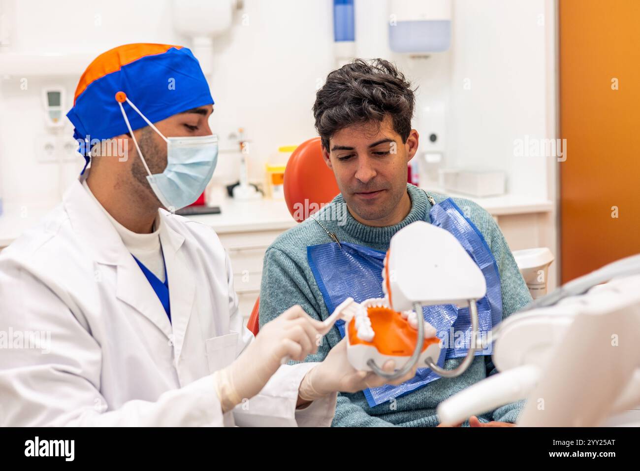 Dentist wearing a mask and bouffant cap demonstrating proper tooth ...