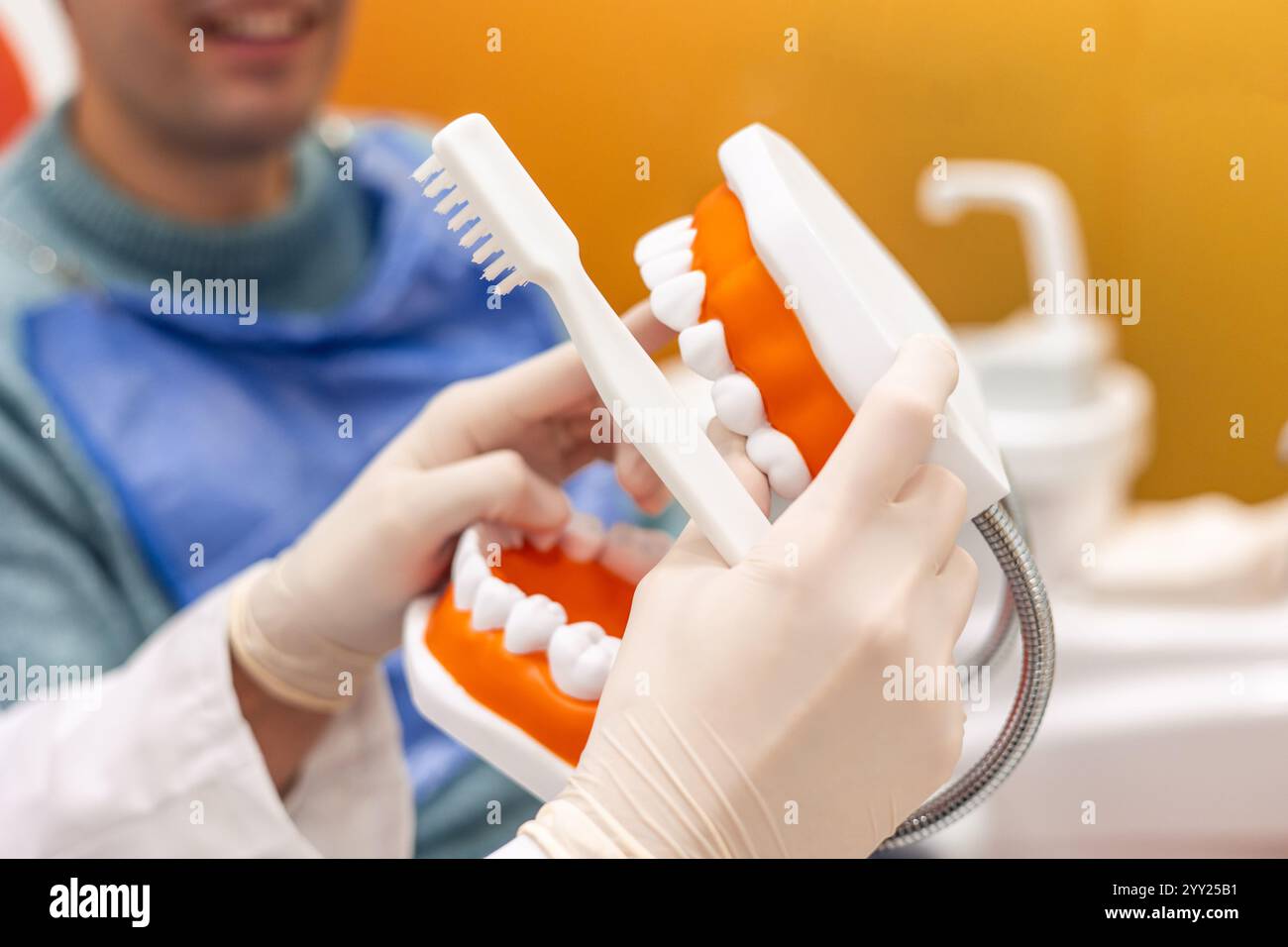 Dentist wearing white gloves showing how to correctly brush teeth using ...