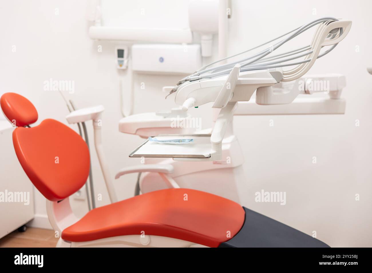 Empty red dentist chair with tools hanging above it stands in modern ...