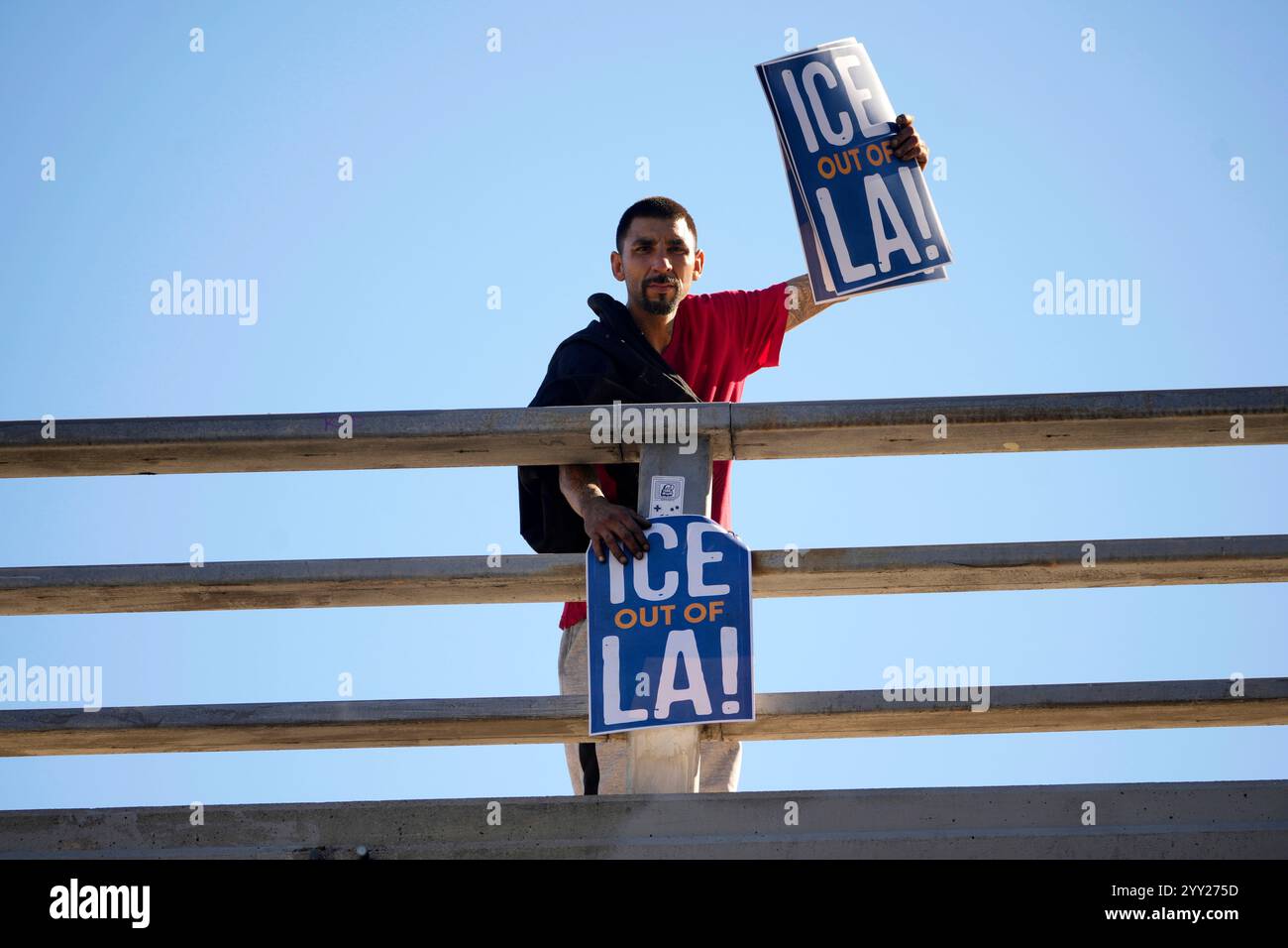 A man on an overpass holds signs against the U.S. Immigration and ...
