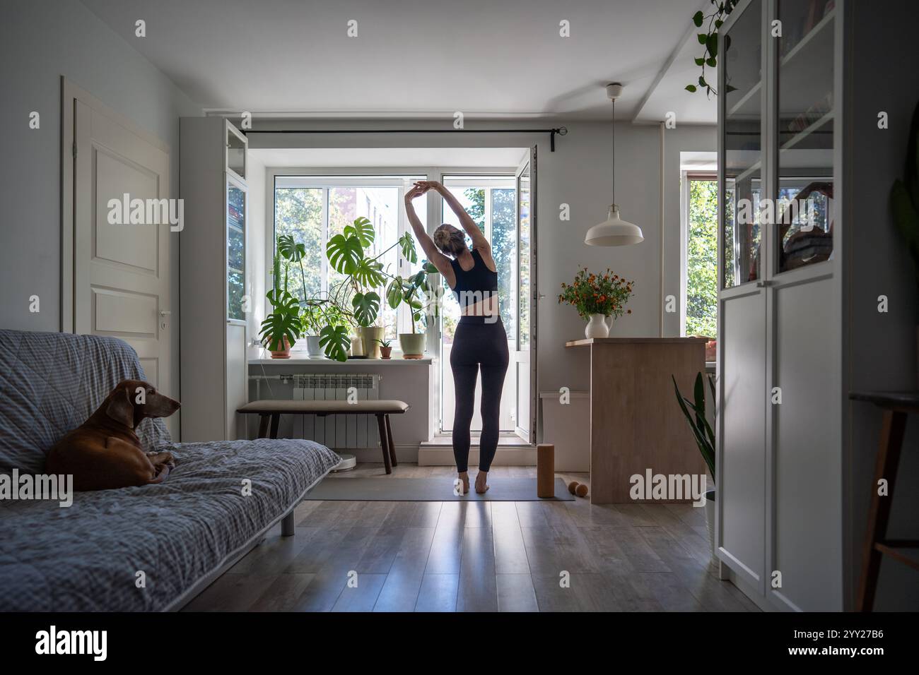 Stretching woman with arms raised above head leans to side on mat while ...