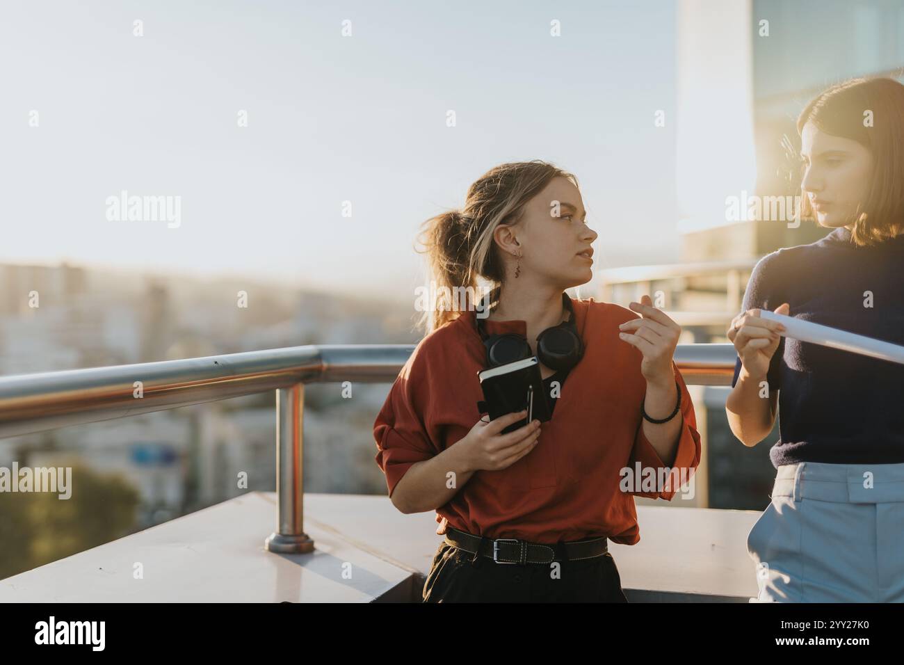 Two business colleagues are standing on a high-rise balcony ...