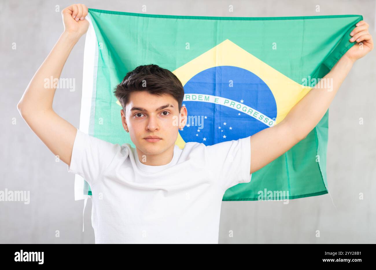 Focused young guy holding flag of Brazil Stock Photo - Alamy