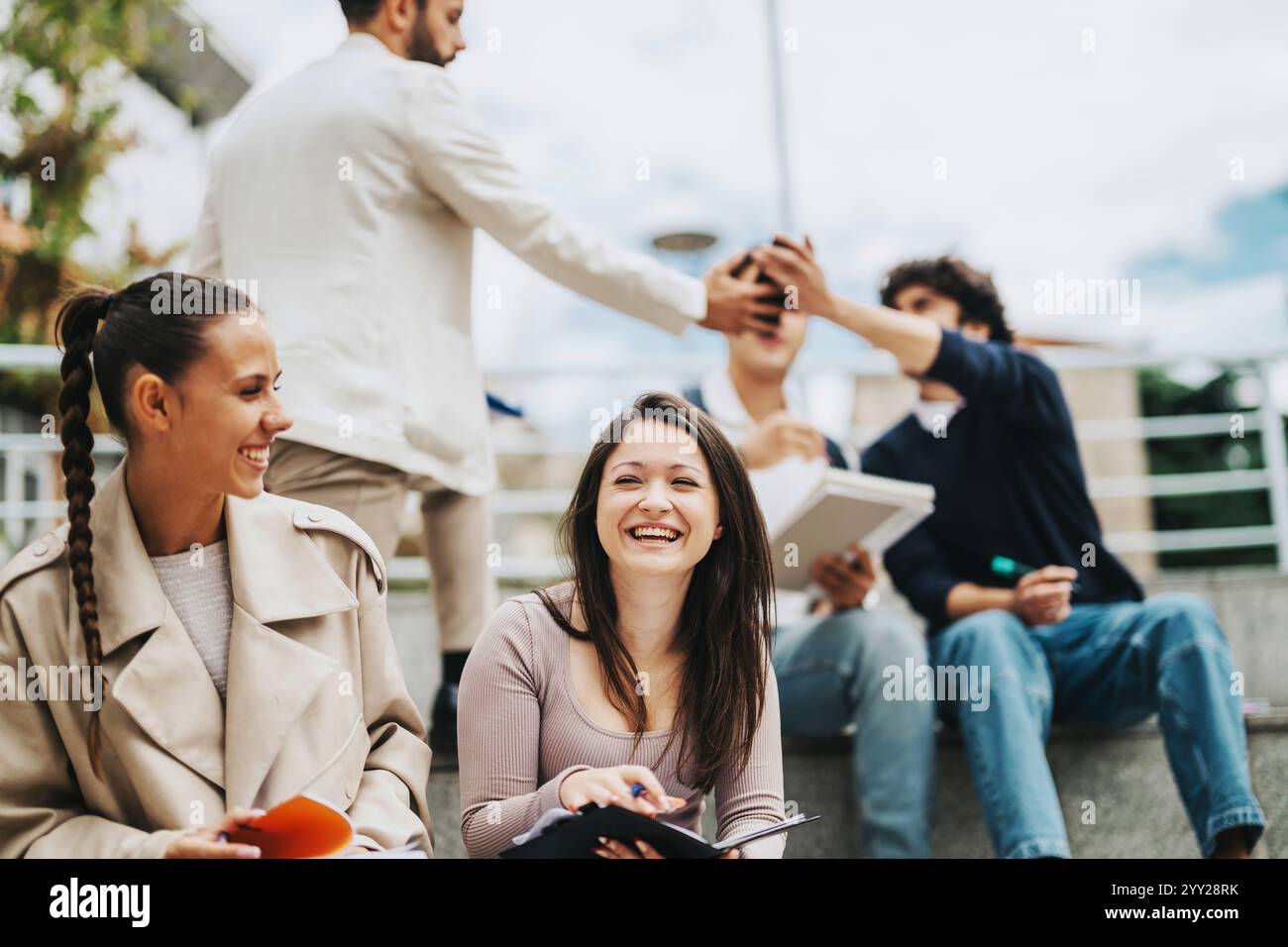 Group of cheerful students collaborating outdoors with a supportive ...