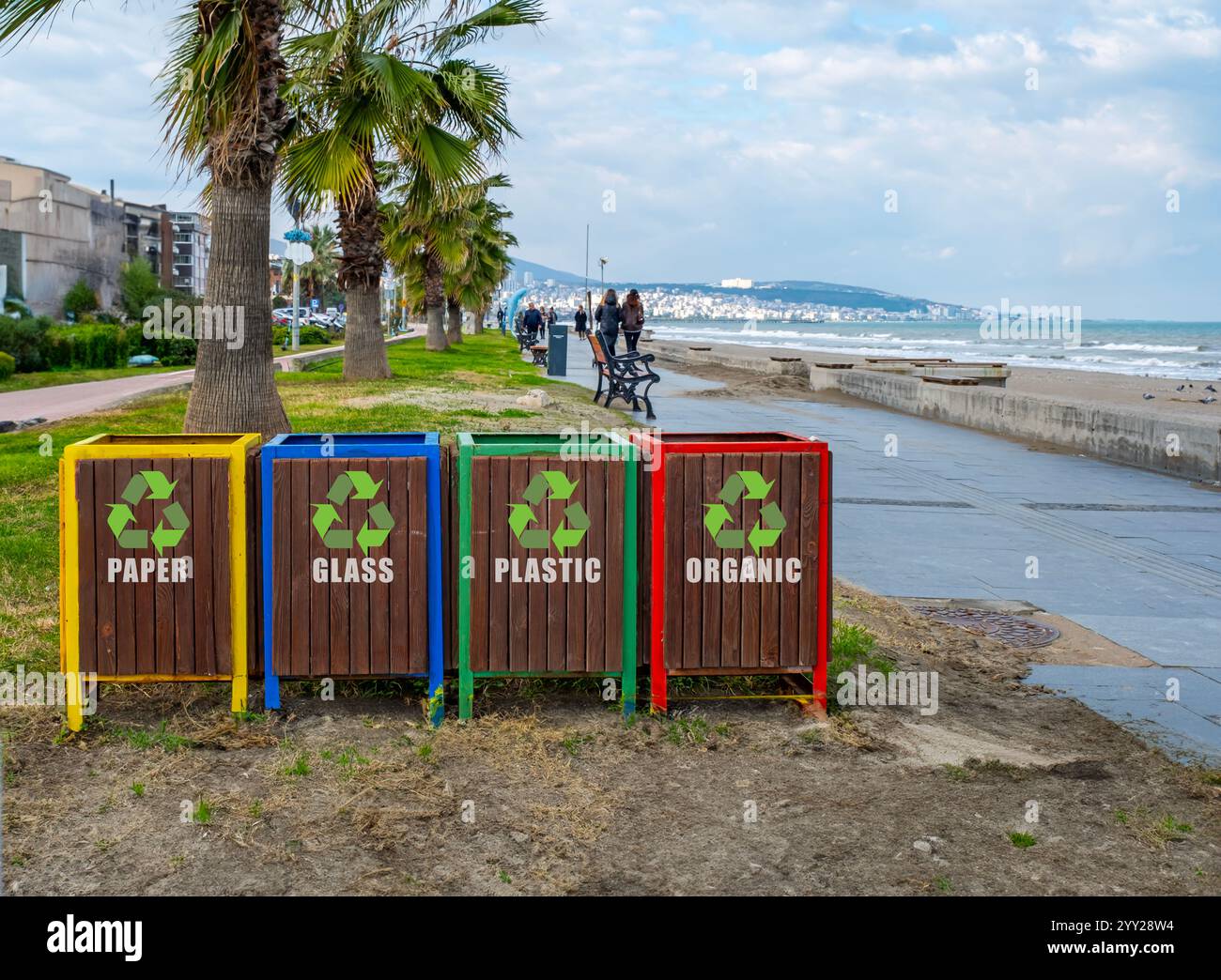 A row of recycling bins are lined up on the beach. The bins are labeled ...
