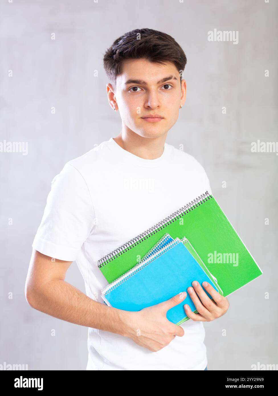 Portrait of guy in casual clothes posing with notebooks in studio Stock ...