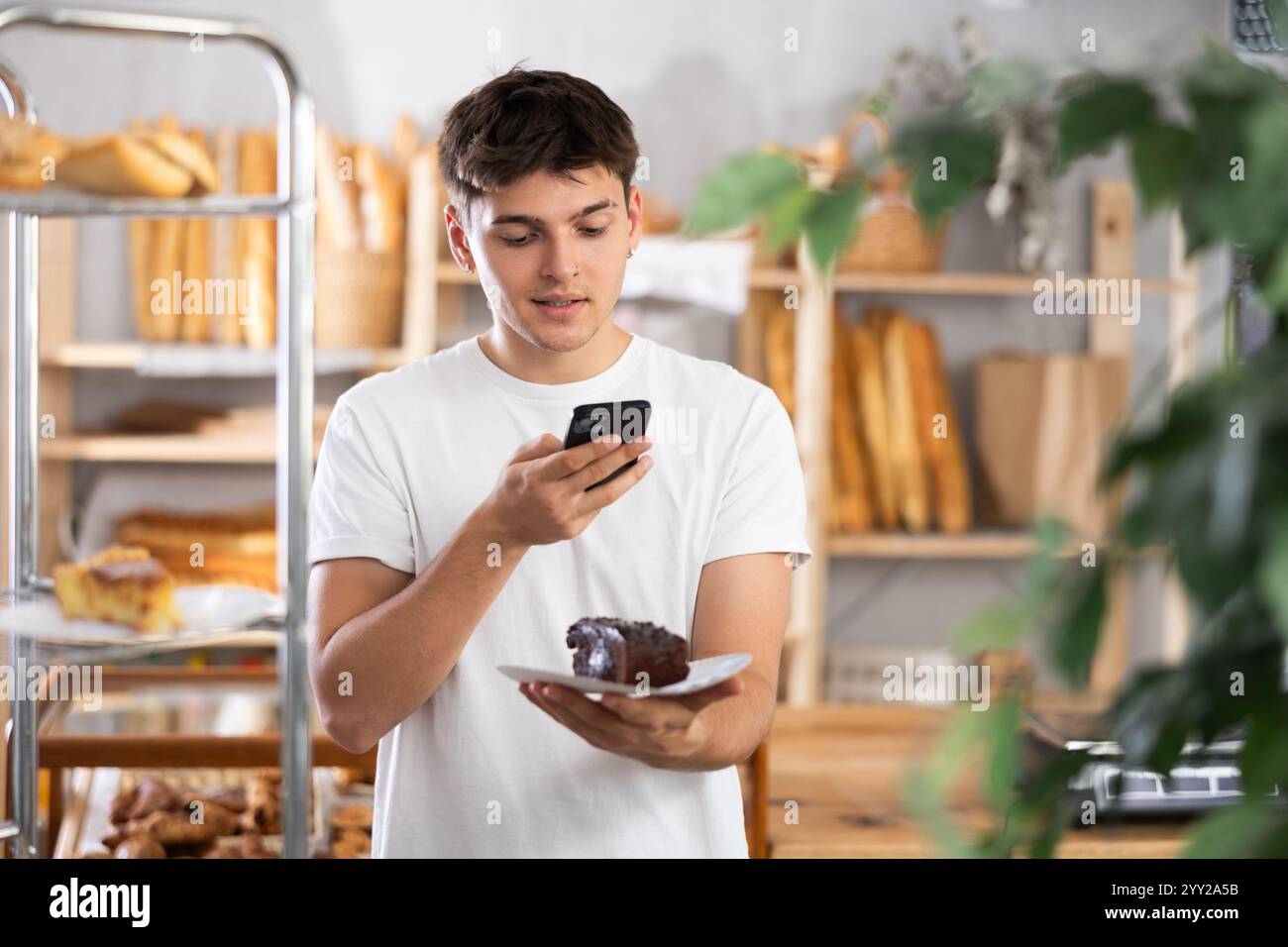 Male customer takes photo of sweet pie using smartphone in interior of ...