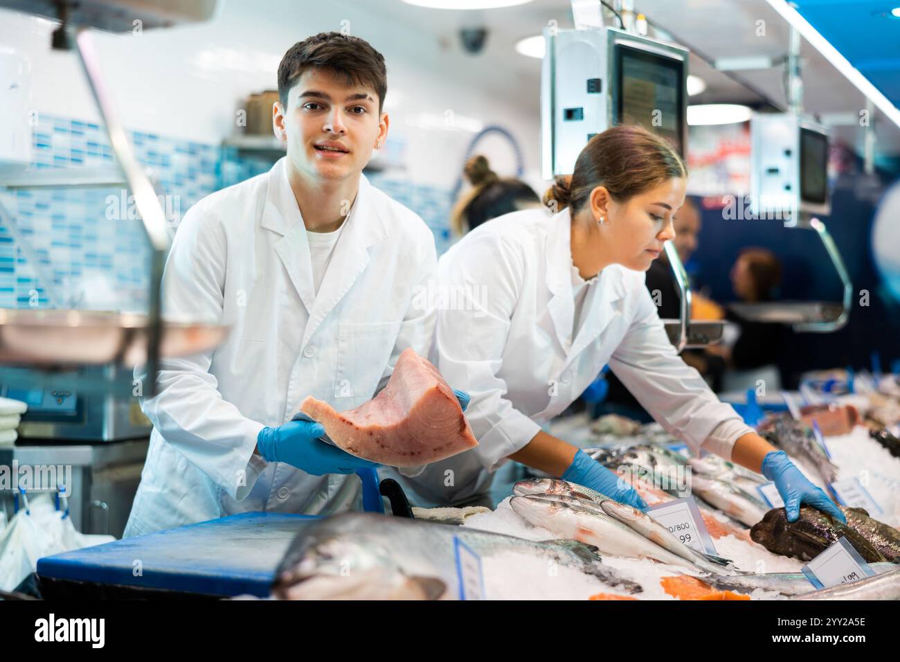 Male seller demonstrates large piece of tuna fillet at fish market ...
