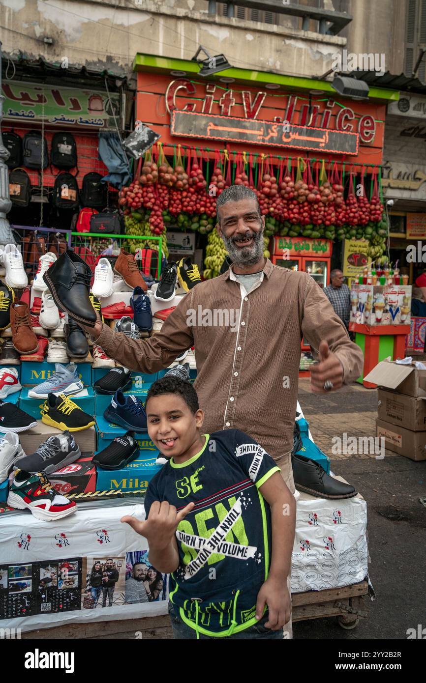 A smiling vendor and a cheerful boy pose at a bustling Alexandria ...