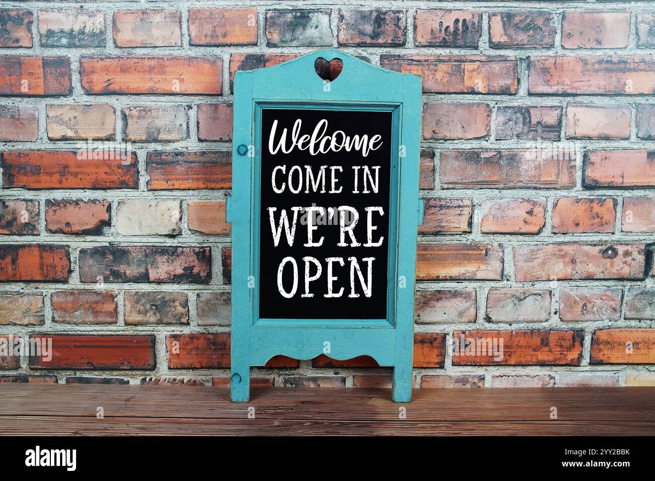 Welcome We're Open text on blackboard easel stand on wooden and old ...