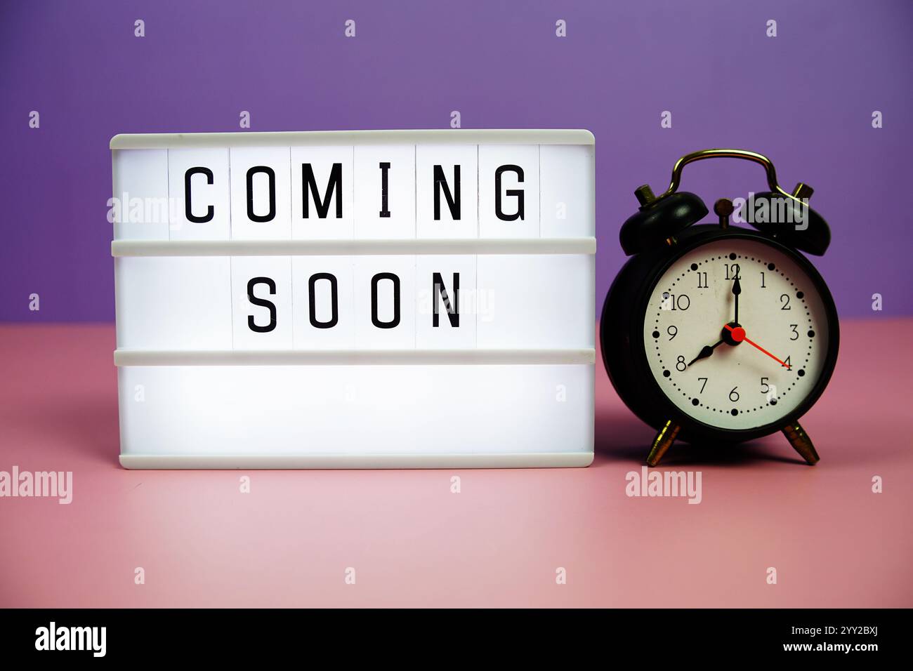 Coming Soon letterboard text on LED Lightbox and alarm clock on pink ...