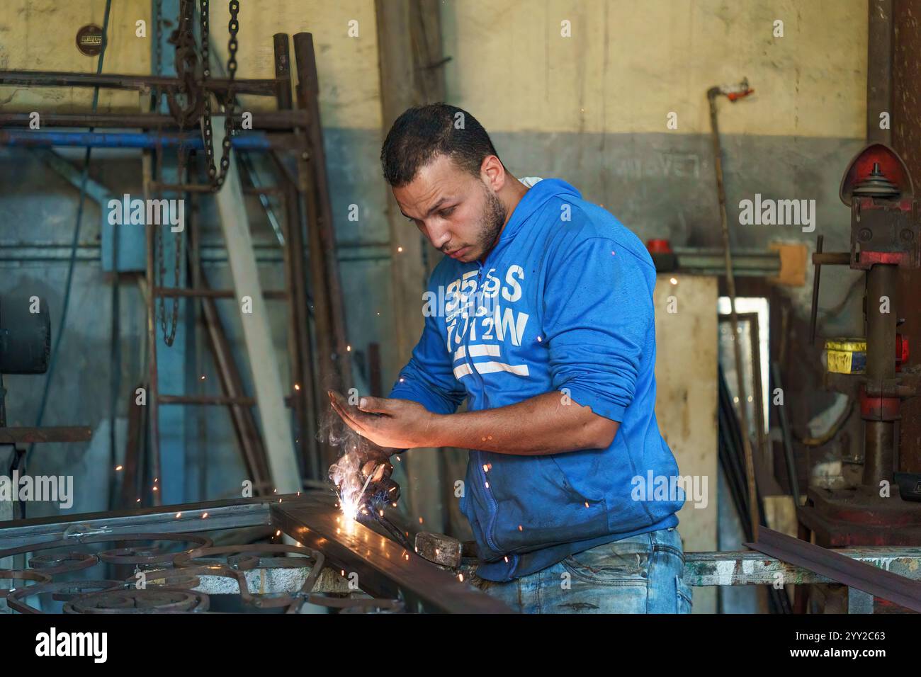Young Egyptian welder in Alexandria skillfully welding metal, sparks ...