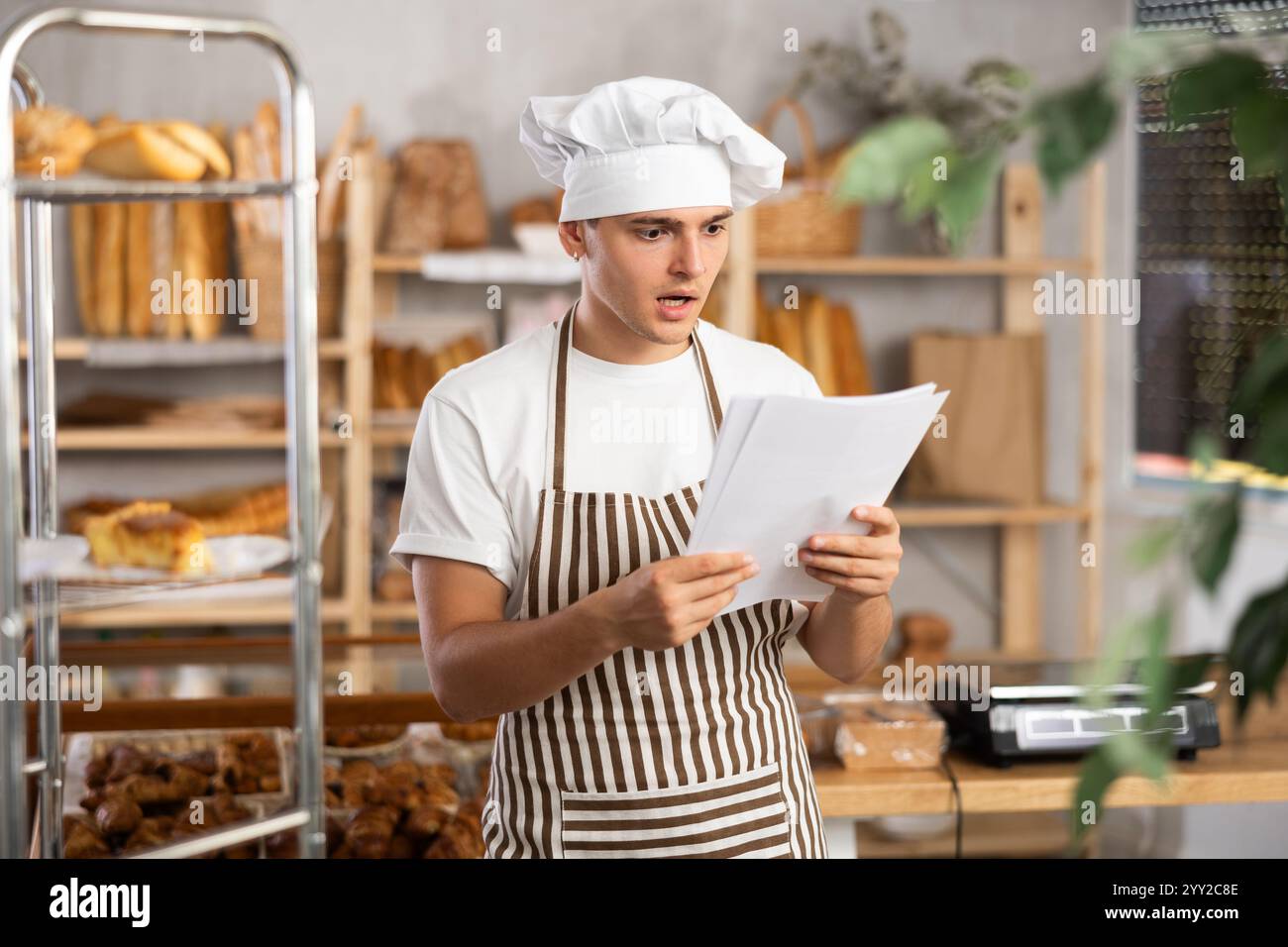 Frustrated male owner of bakery reads documents and reflects, makes ...