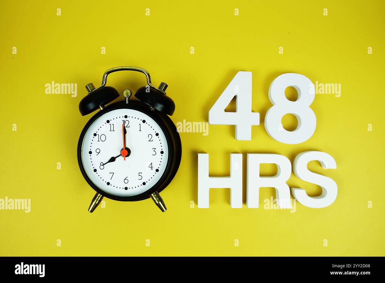 48 Hrs alphabet letters and alarm clock top view on yellow background ...