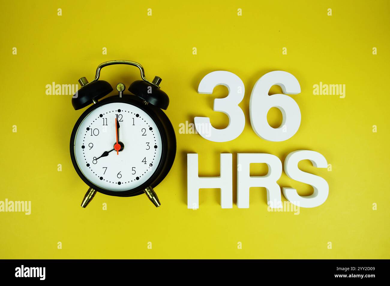 36 Hrs alphabet letters and alarm clock top view on yellow background ...