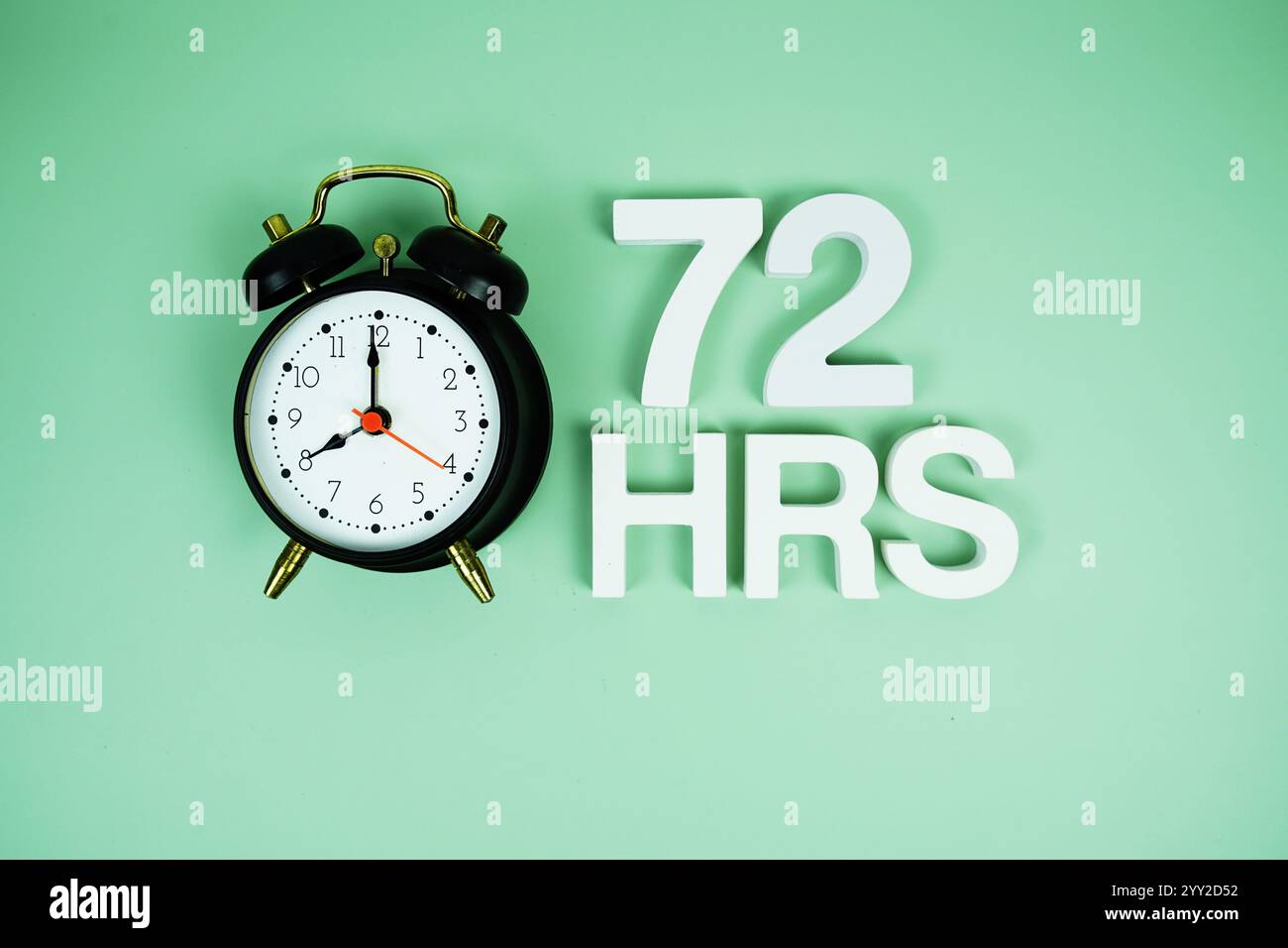 72 Hrs alphabet letters and alarm clock top view on green background ...