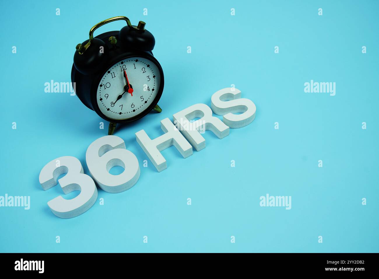 36 Hrs alphabet letters and alarm clock top view on blue background ...