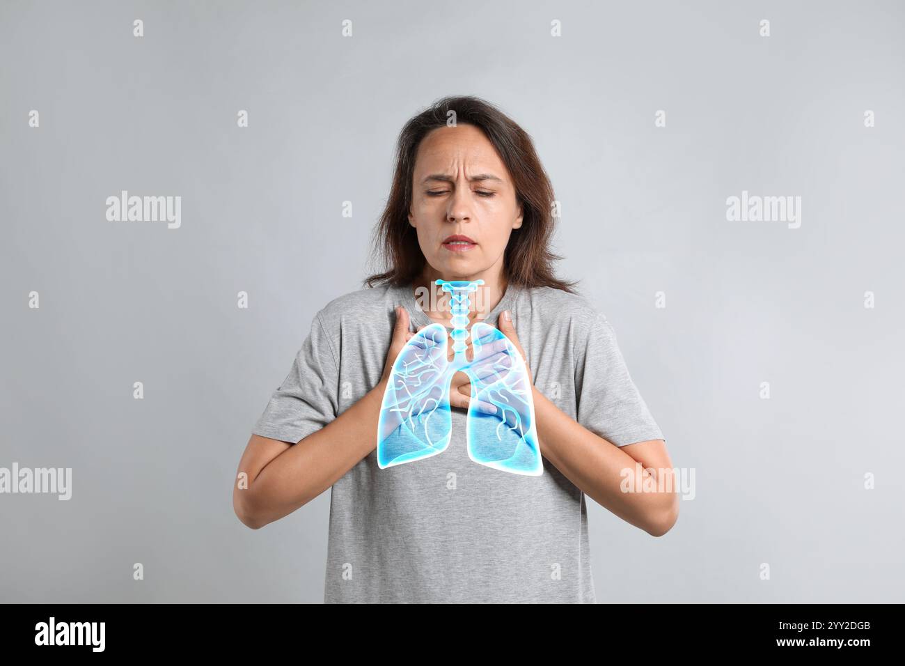 Woman with asthma suffering from difficulty breathing on grey ...