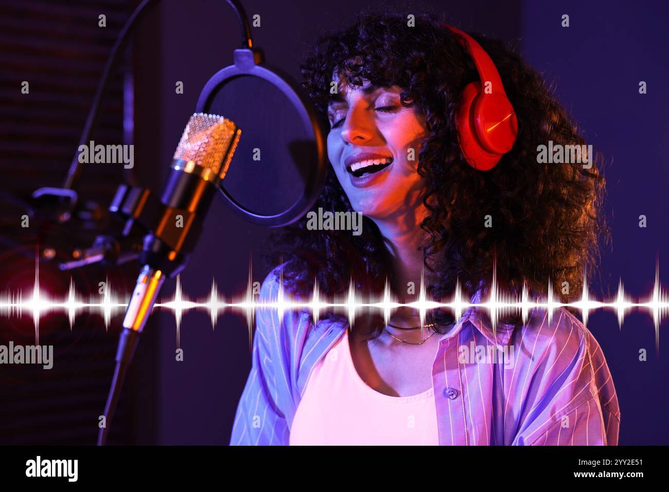 Vocalist with headphones singing into microphone in professional record ...