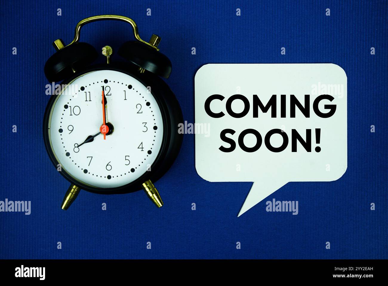Coming Soon text on speech bubble with alarm clock top view on blue ...
