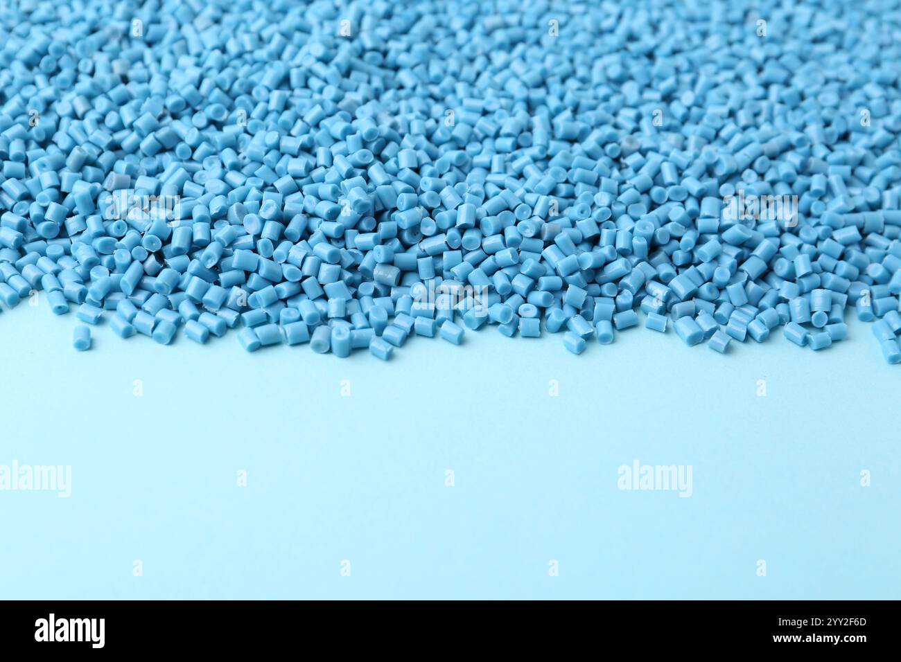 Pile of plastic granules on light blue background, closeup. Space for ...