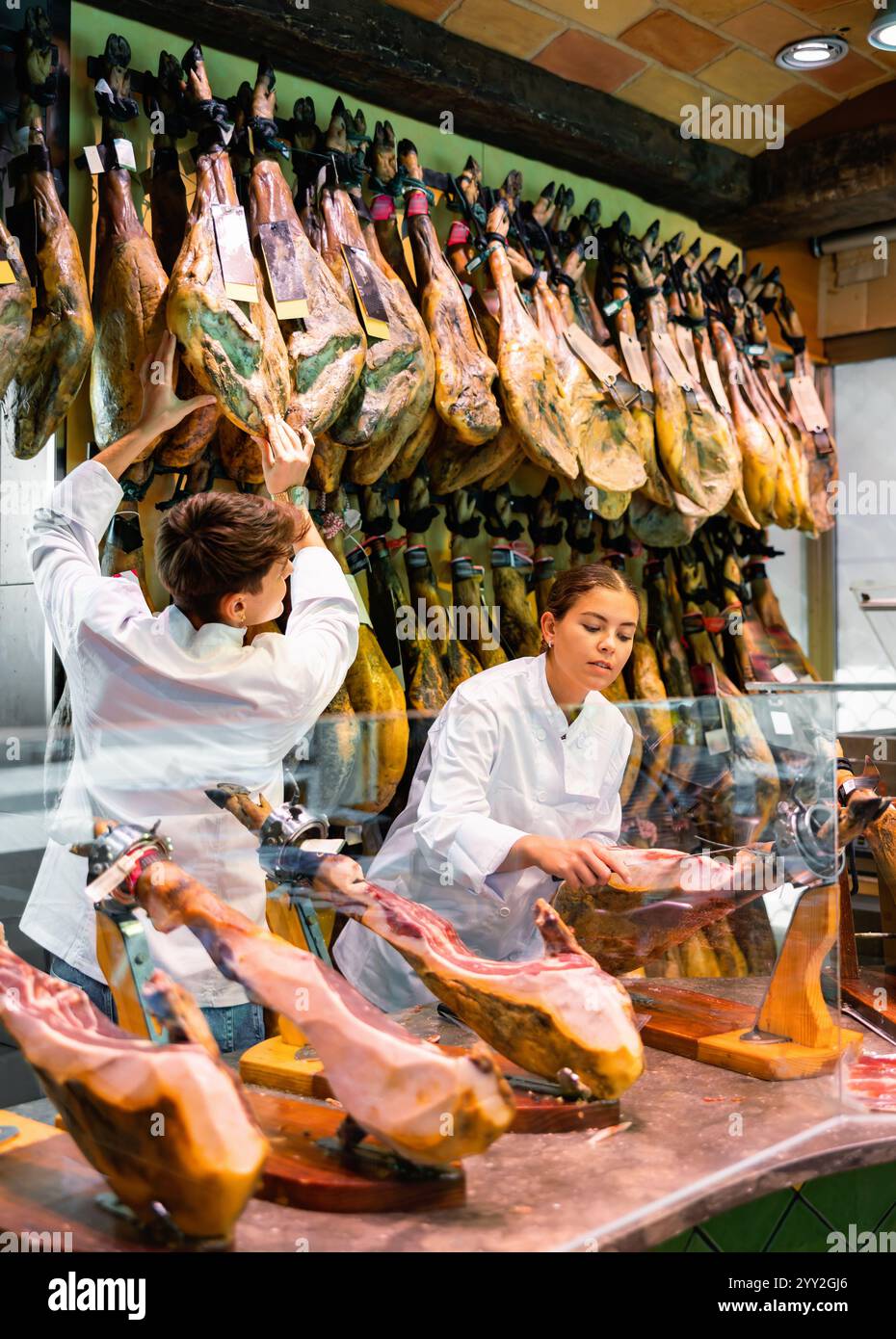 Young salesgirl and salesman of butcher shop selling Iberian jamon ...