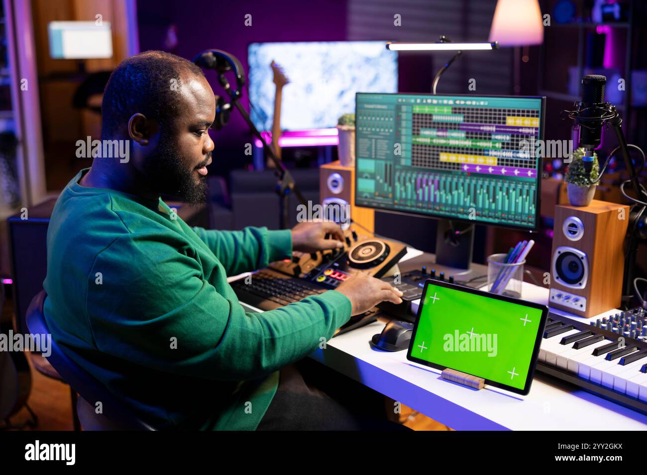 Confident musician producing tracks on mixing console in home studio ...