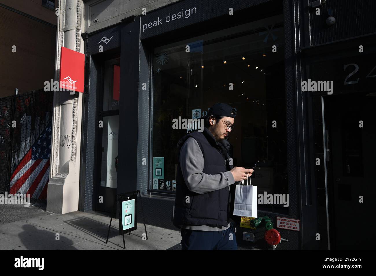 New York, USA. 18th Dec, 2024. A man walks past the Peak Design retail store located in the SoHo ...